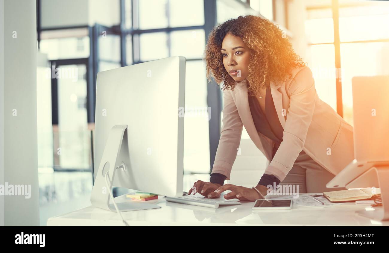 Hard work pays off. a young businesswoman using a computer at her work ...