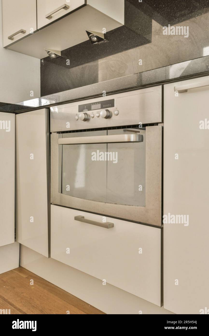 a white kitchen with an oven and wood floor in the corner, taken from ...