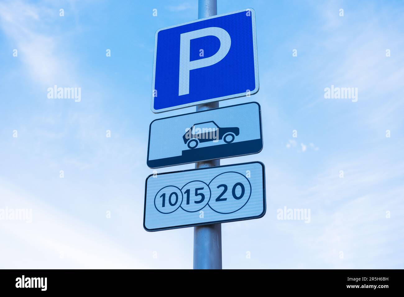 A grey post with several parking signs including a white letter "P" in ...