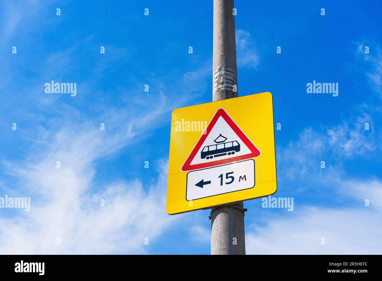 A tram stop sign on a concrete pillar against a blue sky backdrop ...