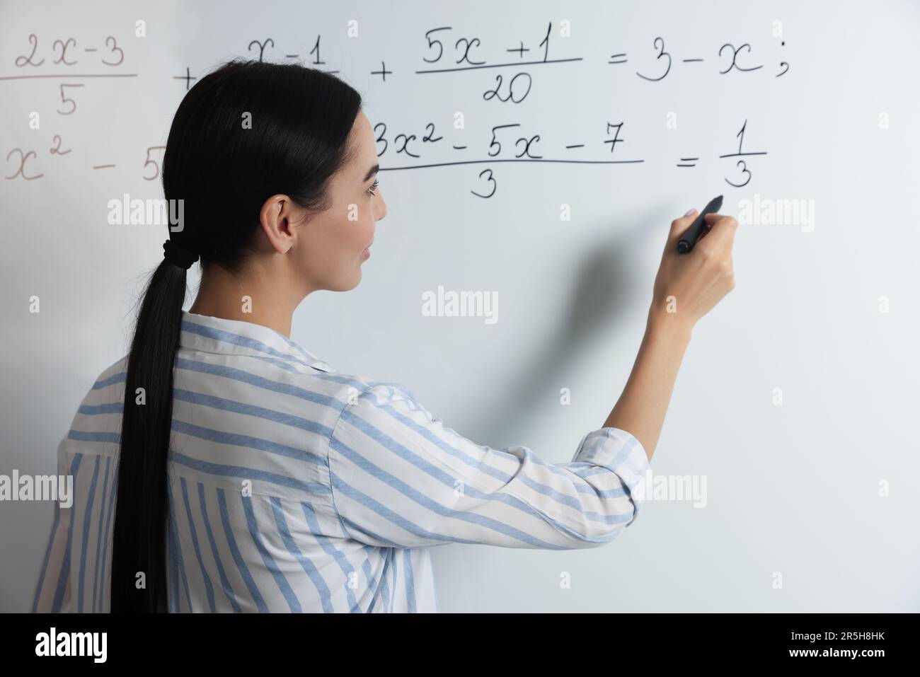 Young teacher explaining mathematics at whiteboard in classroom Stock ...
