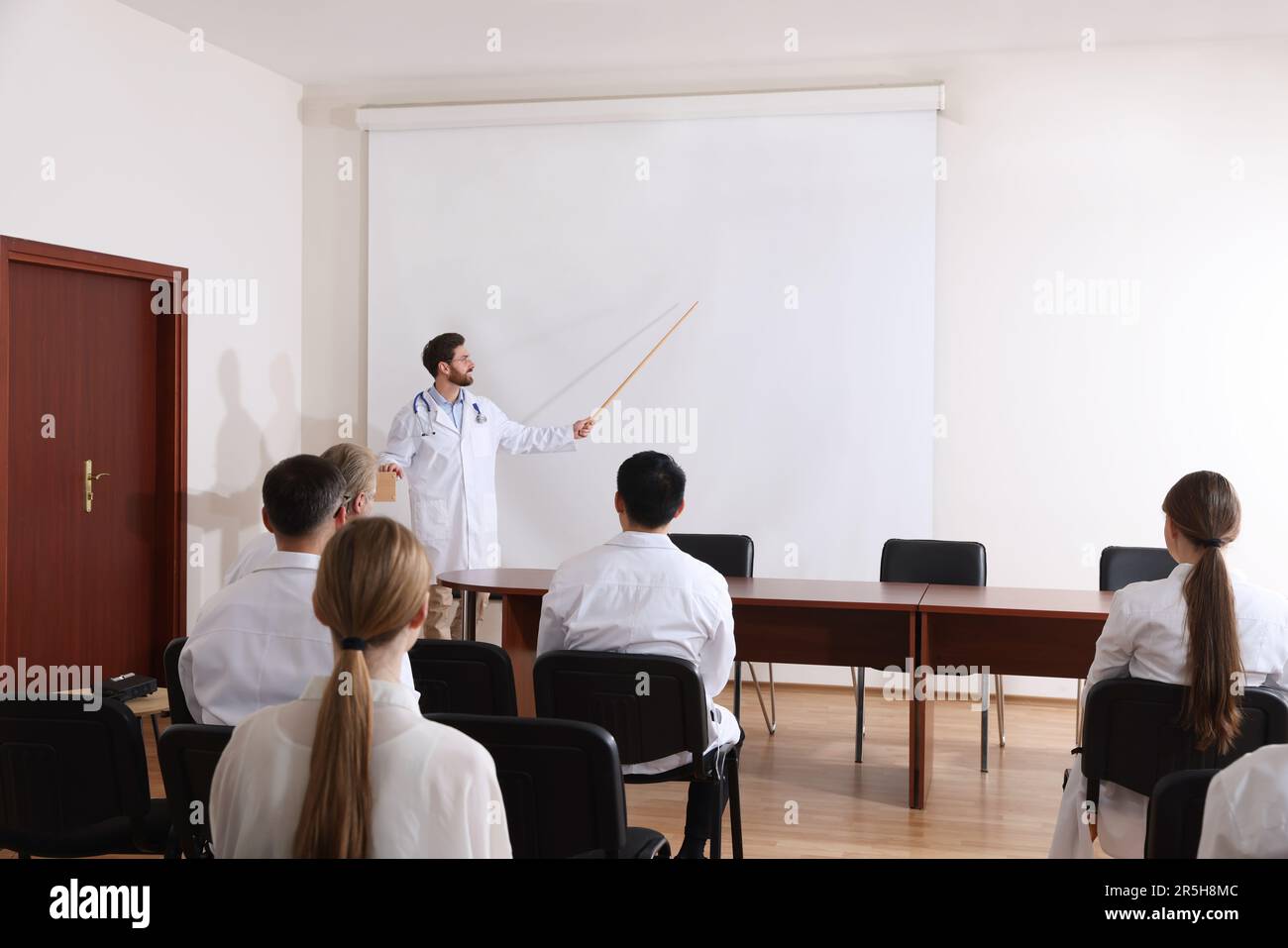 Doctor giving lecture in conference room with projection screen Stock ...