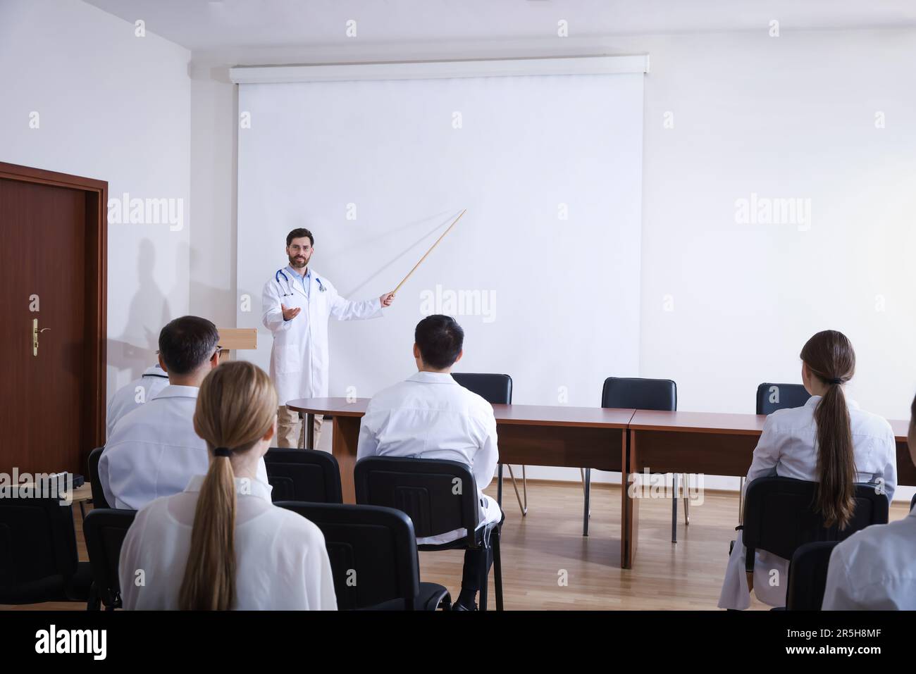 Doctor giving lecture in conference room with projection screen Stock ...