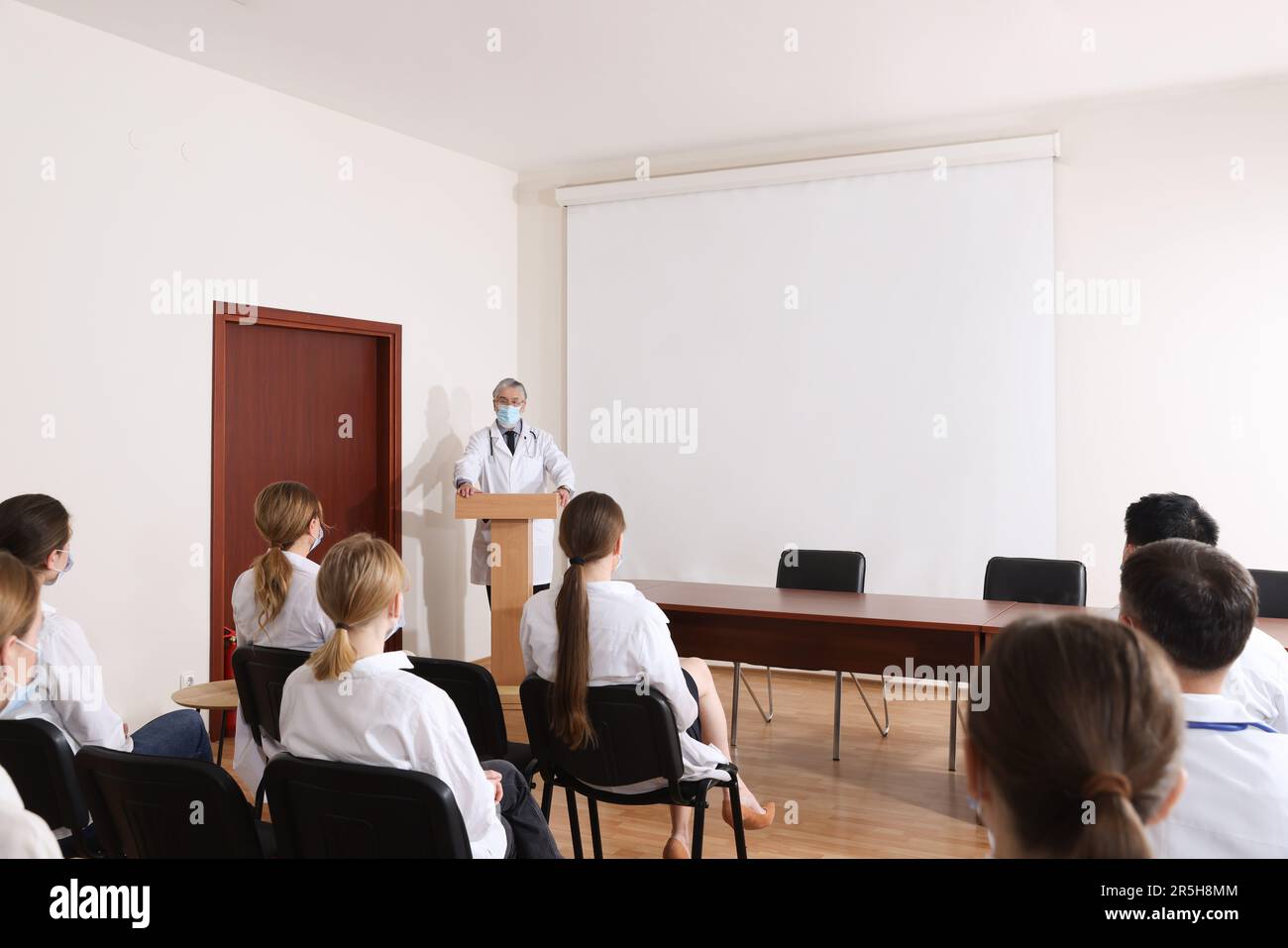 Senior doctor giving lecture near projection screen in conference room ...