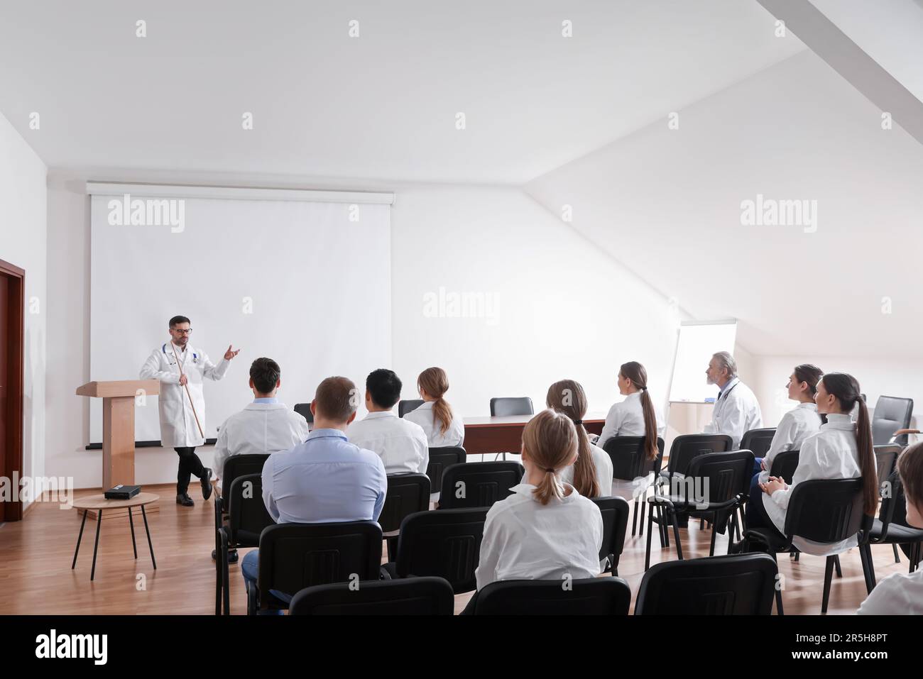 Doctor giving lecture in conference room with projection screen Stock ...