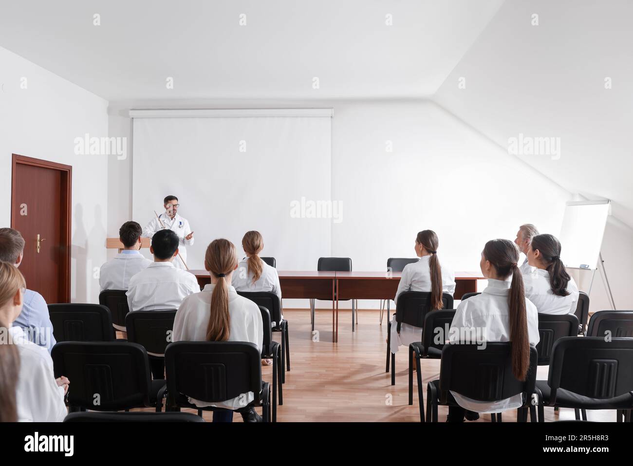 Doctor giving lecture in conference room with projection screen Stock ...