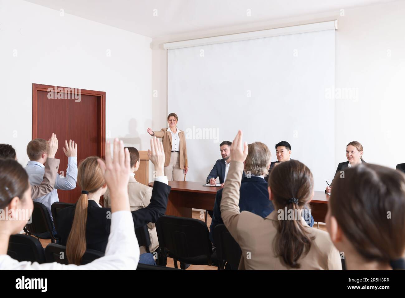 People raising hands to ask questions at business conference in meeting ...