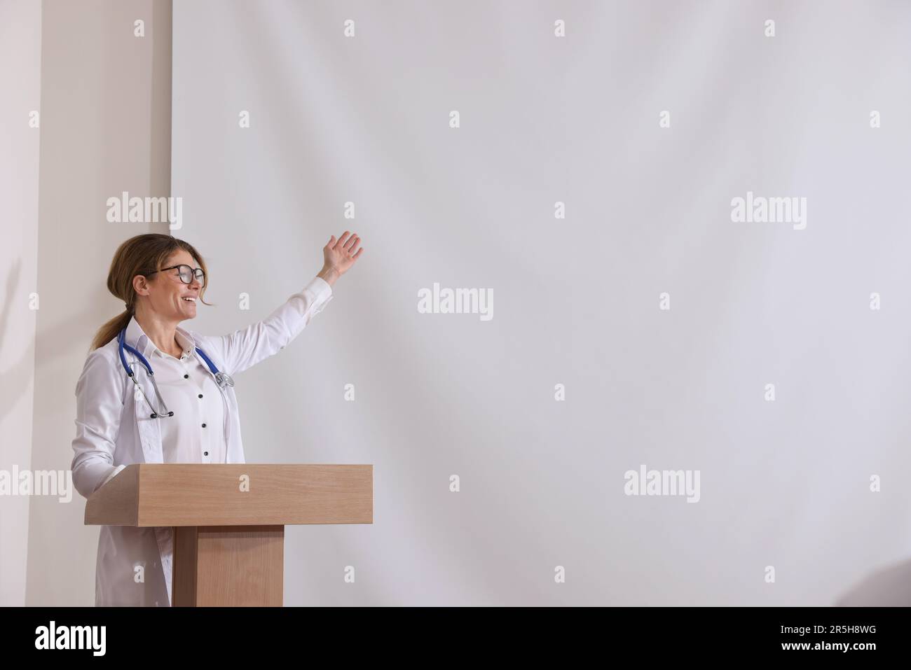 Doctor giving lecture near projection screen in conference room, space ...