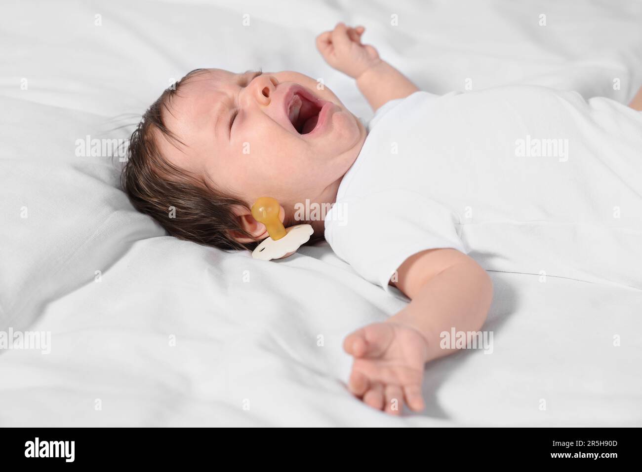 Cute little baby crying on soft bed Stock Photo - Alamy
