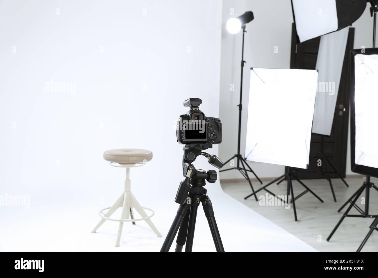 Tripod with camera, bar stool and professional lighting equipment in ...
