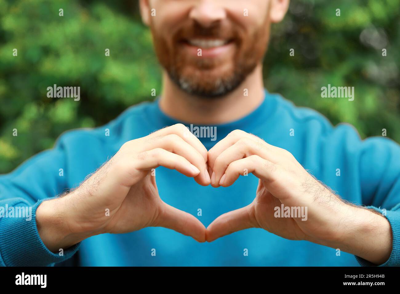 Happy man making heart with hands outdoors, closeup Stock Photo - Alamy