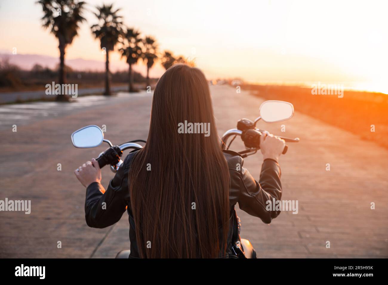 Woman riding motorcycle at sunset, back view Stock Photo - Alamy