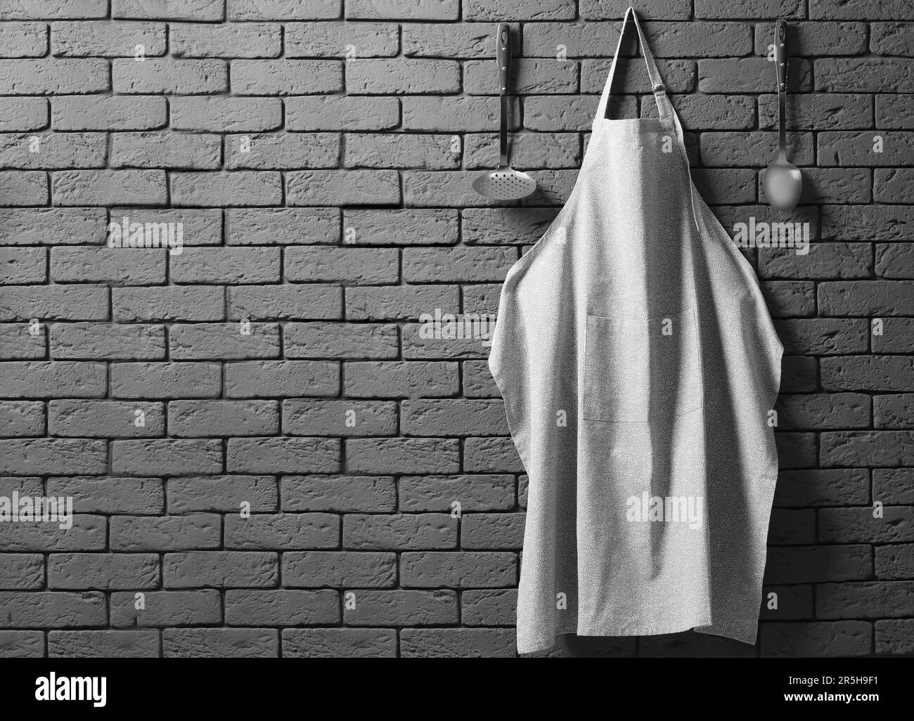 Clean apron with pattern and kitchen tools on grey brick wall Stock ...