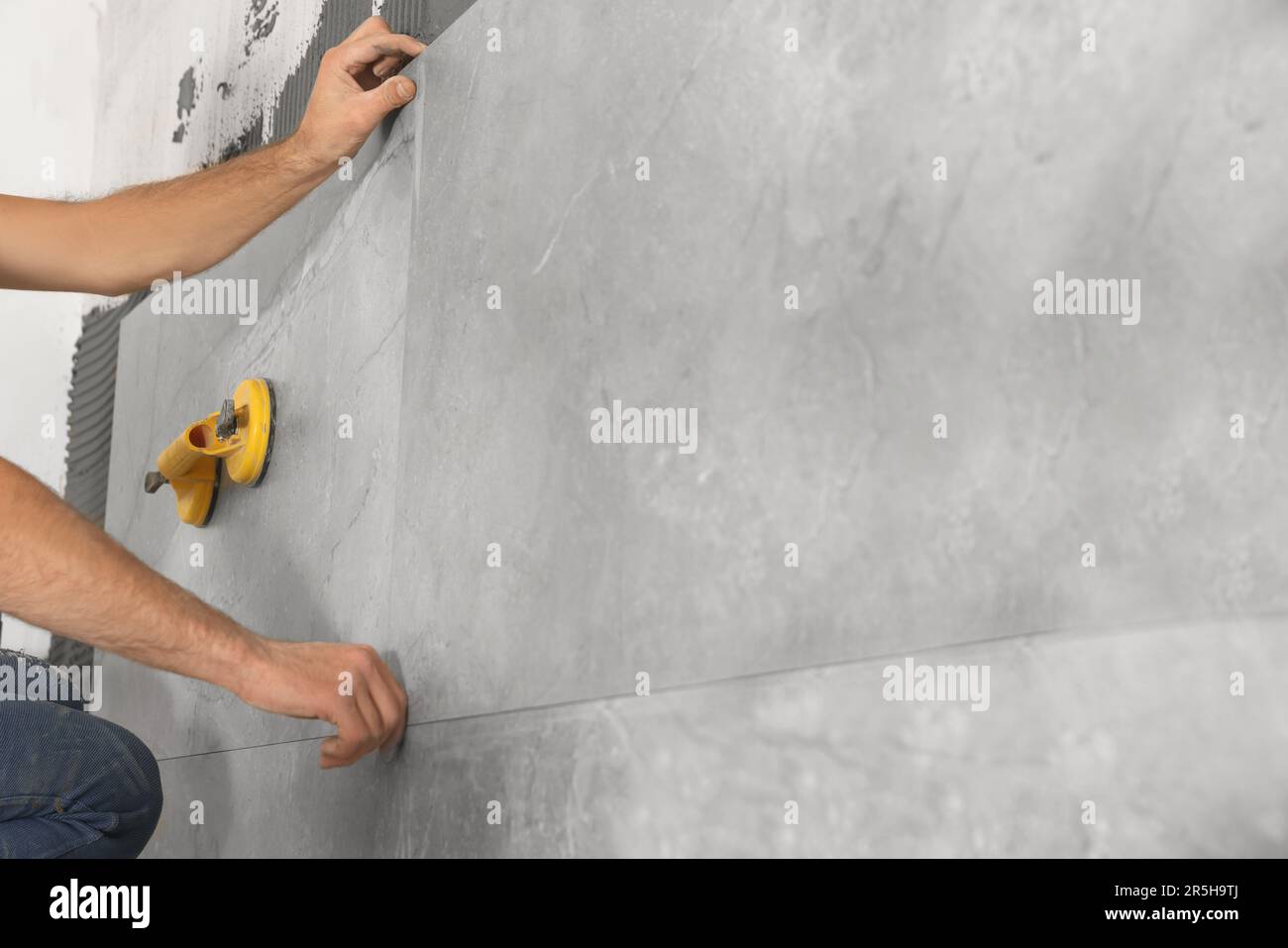Worker installing wall tile with vacuum holder indoors, closeup Stock ...