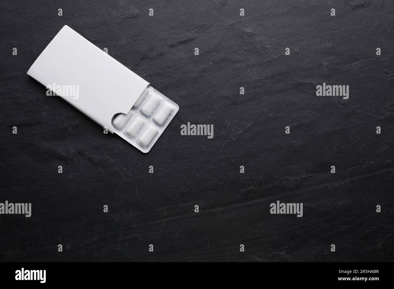 Blister with chewing gums on black table, top view. Space for text ...