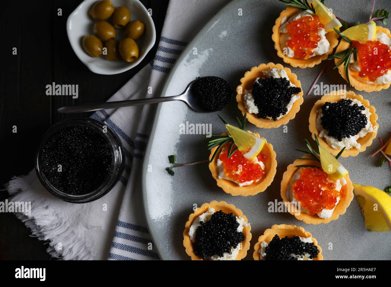 Delicious tartlets with red and black caviar served on dark table, flat ...