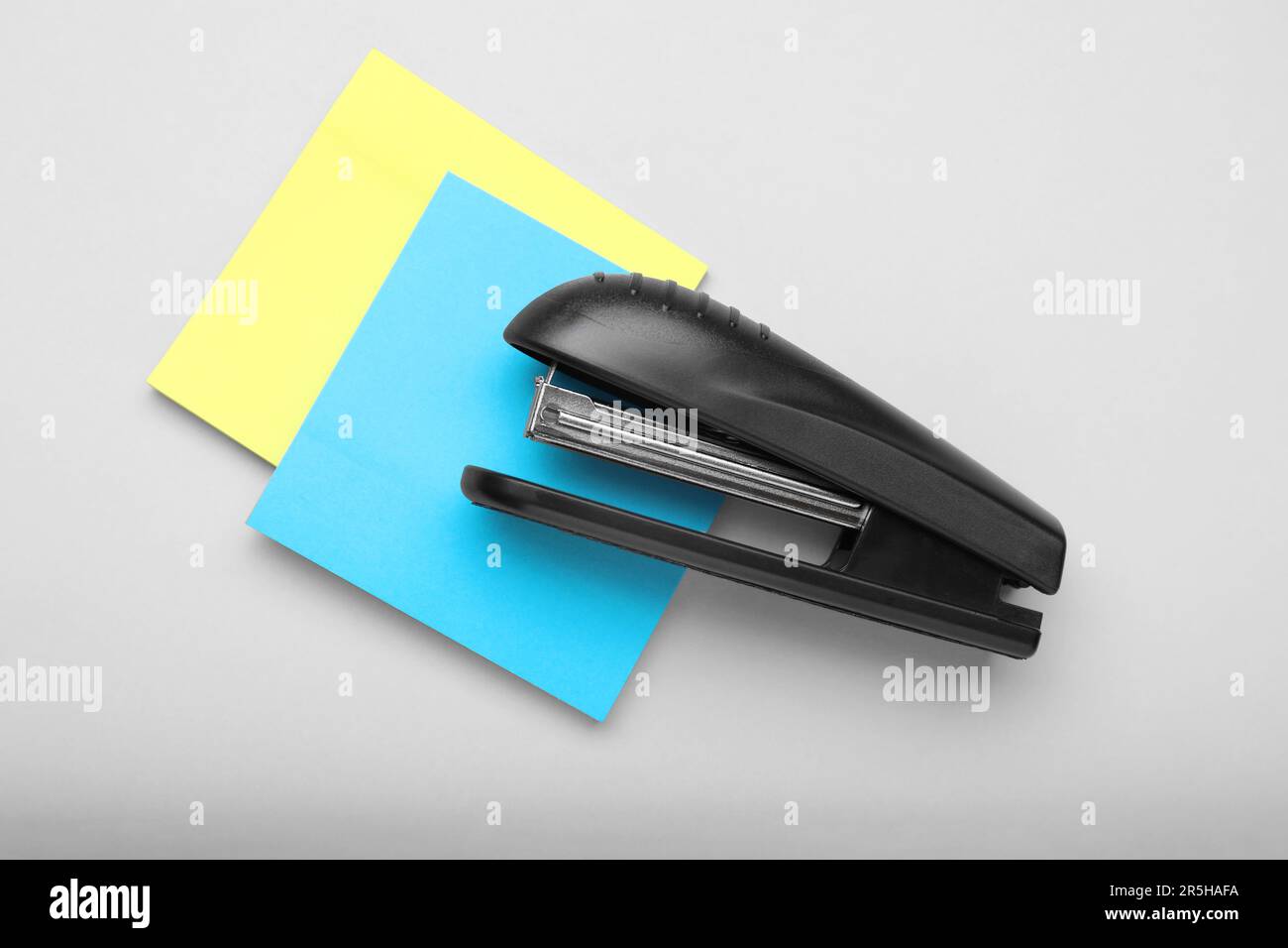 New bright stapler with sticky notes on light grey background, flay lay ...