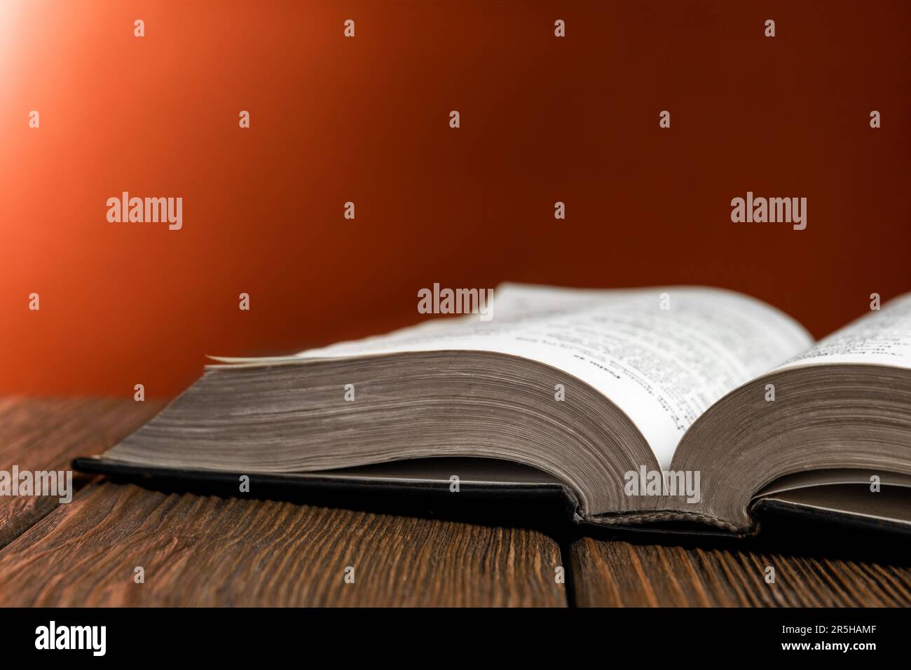 Open Bible on wooden table against brown background, closeup. Space for ...