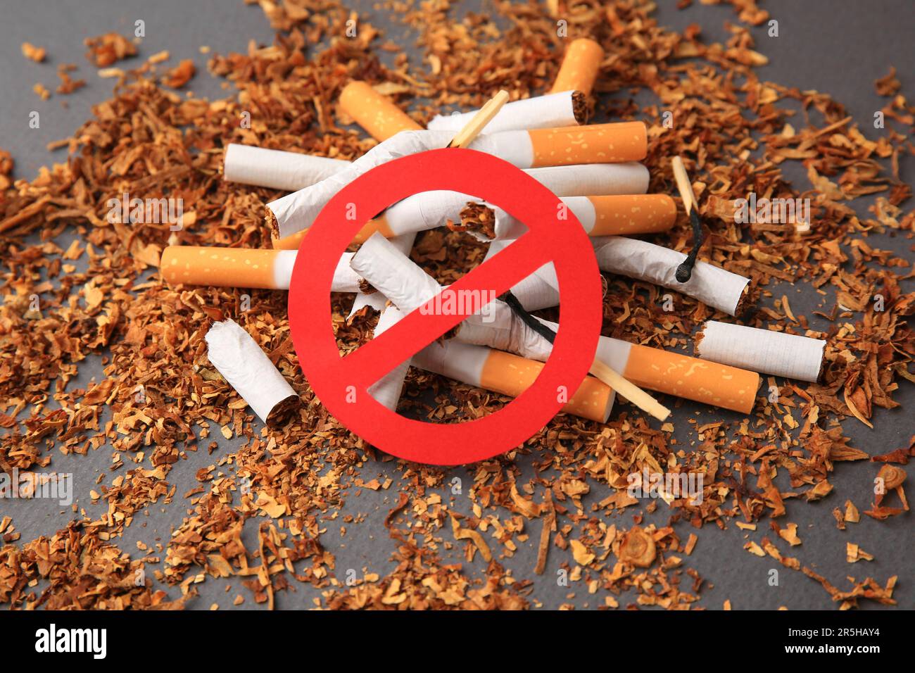 Prohibition sign, broken cigarettes and burnt matches on dark grey ...