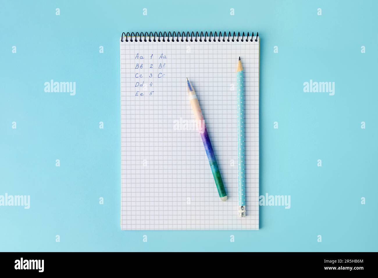 Letters and numbers written in notepad with erasable pens on light blue ...