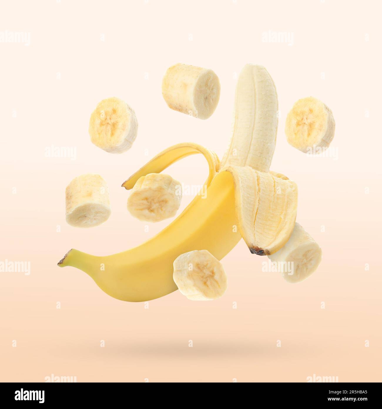 Delicious whole and cut banana fruits falling on light beige background ...