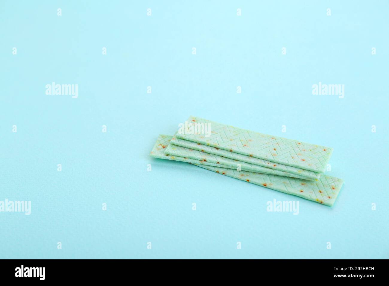 Many sticks of tasty chewing gum on light blue background. Space for ...