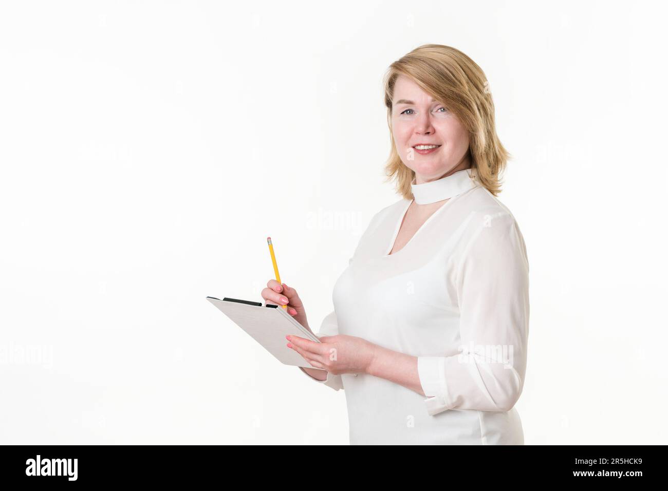 Portrait of businesswoman looking at camera, writes on clipboard with ...