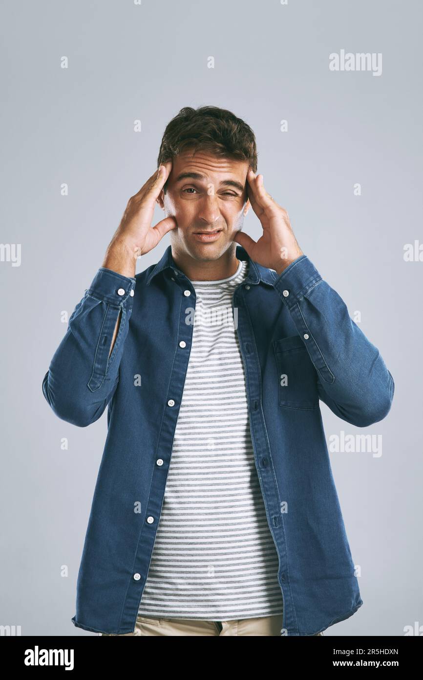 Im losing it. a man suffering from a headache against while posing ...