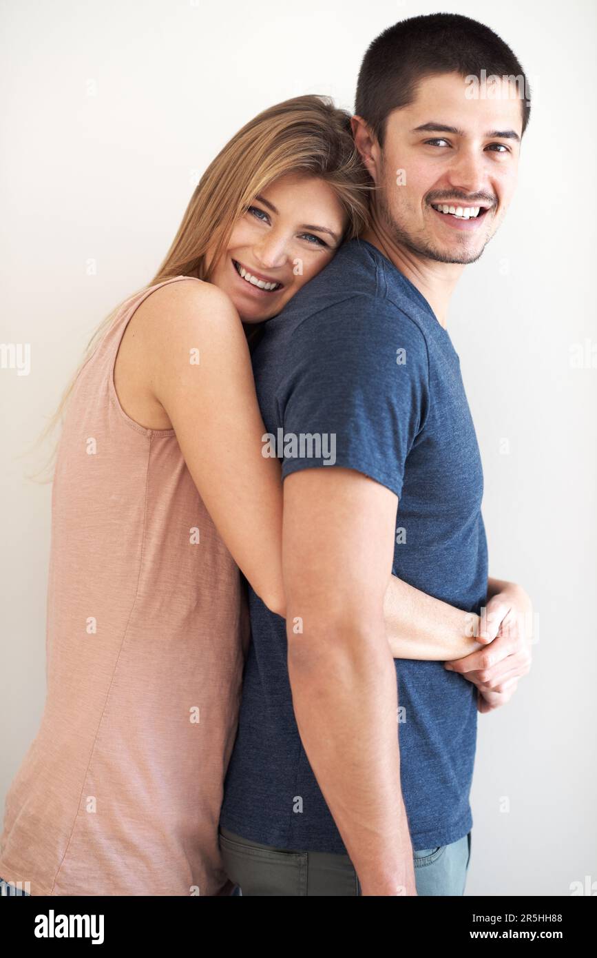 Giving him a loving embrace. Handsome young man smiling while being ...