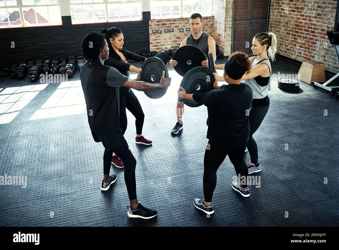Putting in the work. a fitness group using weight plates in their ...