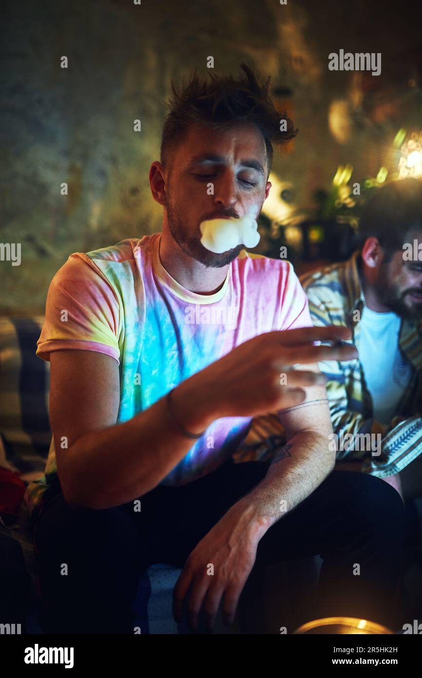A man sitting on the couch with a friend where smoking hi-res stock ...