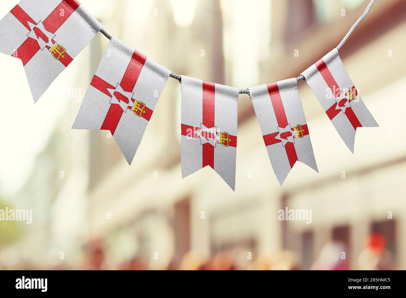 A garland of Northern Ireland national flags on an abstract blurred ...