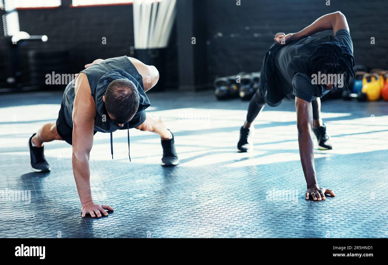 Motivating each other to do better. young men doing push ups in a gym ...