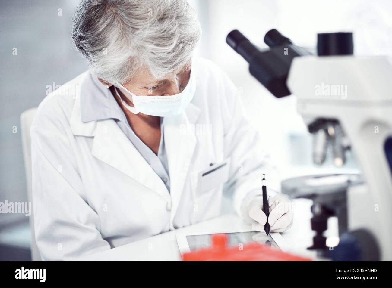 Write down every observation. a focused elderly female scientist ...