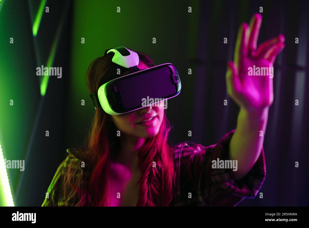 Young woman using a VR headset to explore a digital world, using hand ...