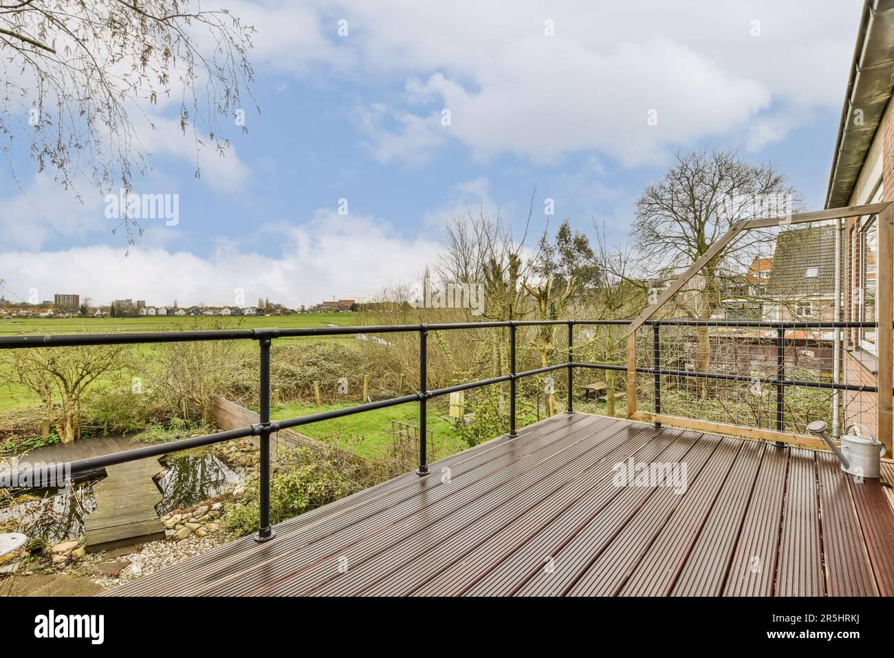 a balcony with wooden decking and black railings on the side of a house ...