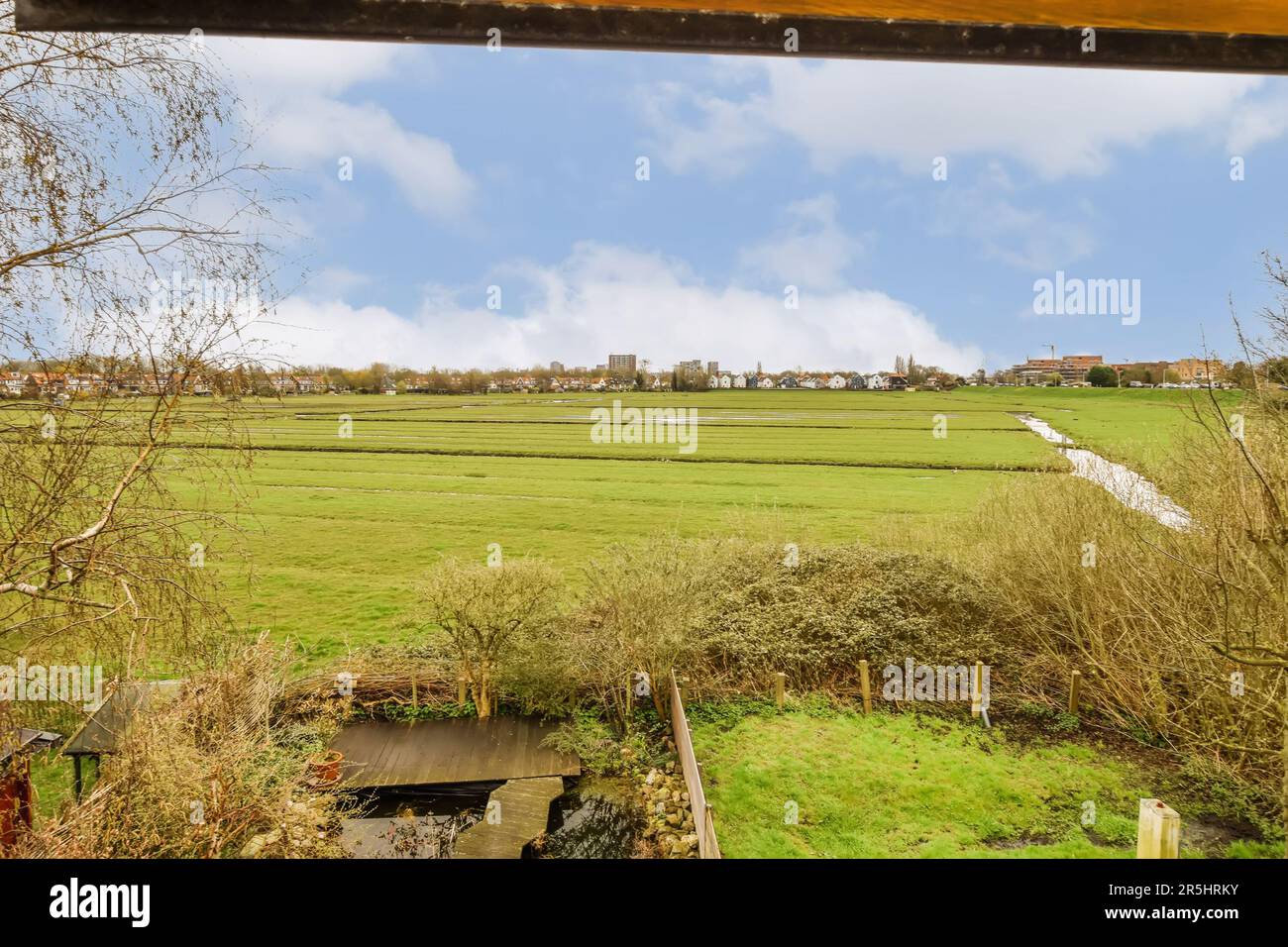 an open field with trees and houses in the distance, taken from a ...