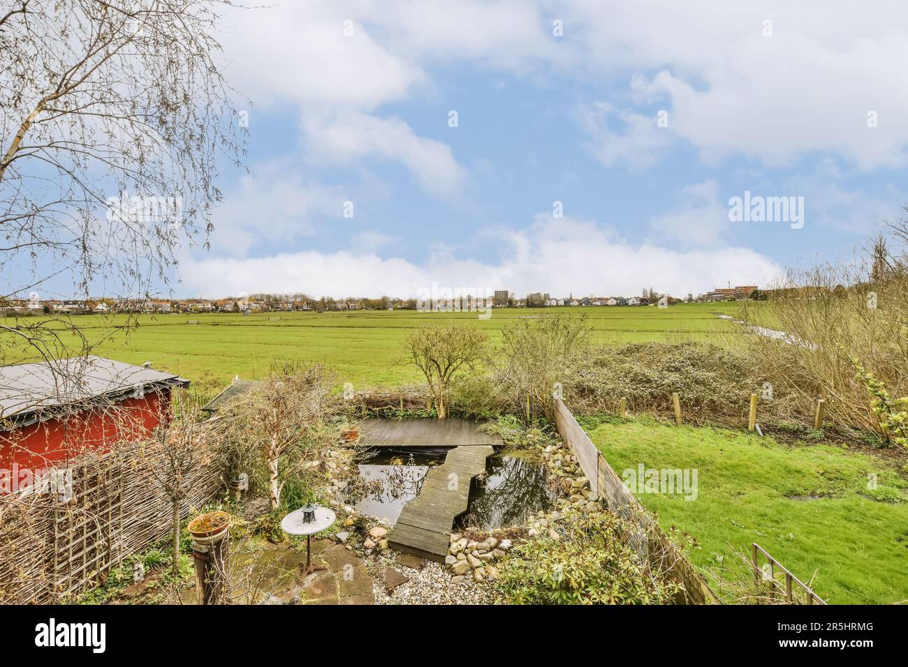 an old red shed in the middle of a green field, with trees and grass on ...