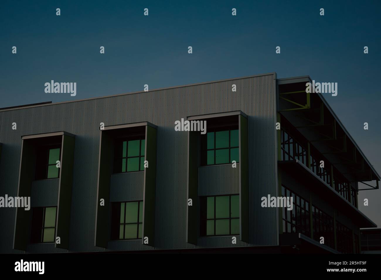 An unassuming office block displays strong lines, an olive green hue ...