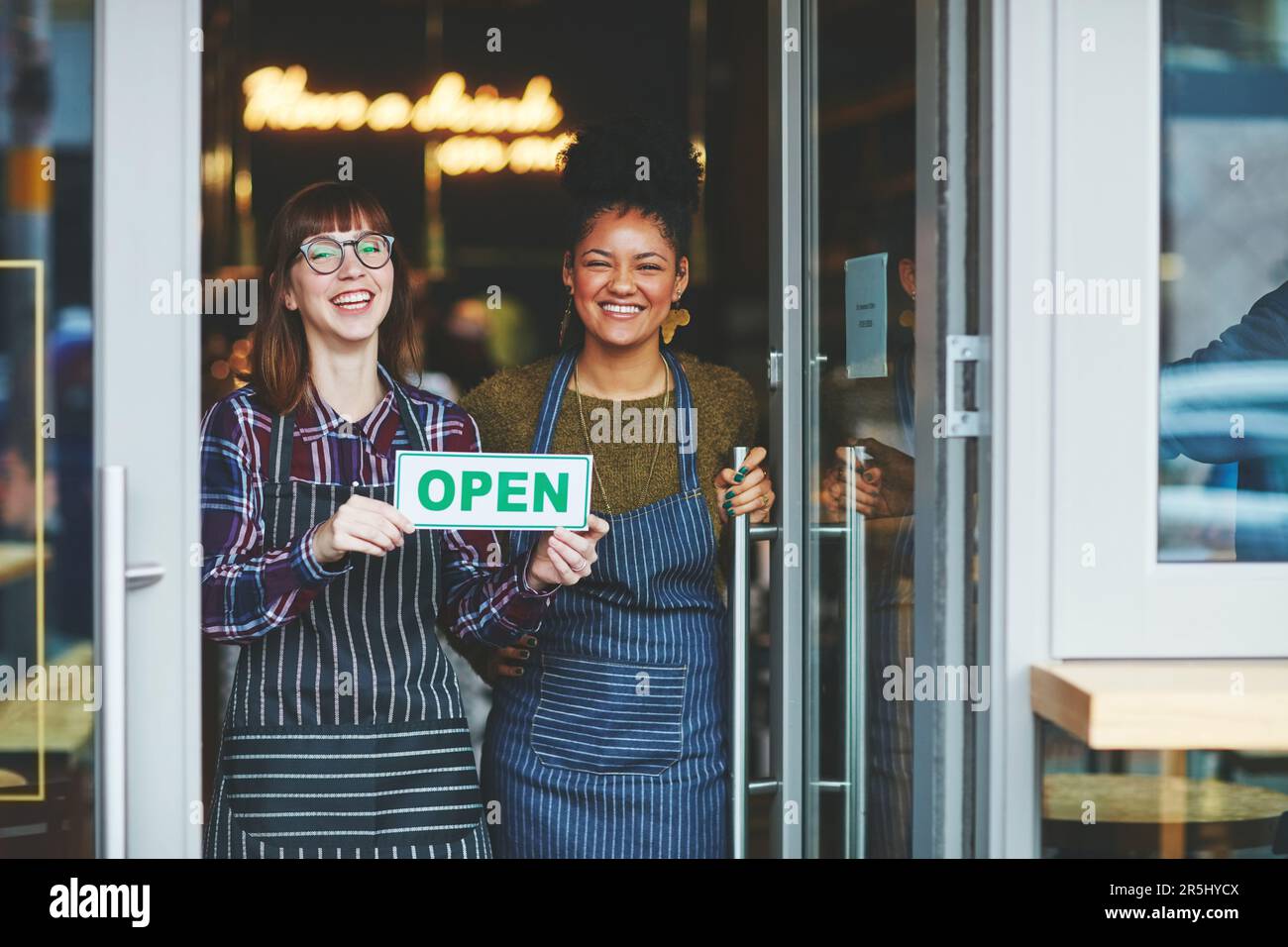Come and visit our new brand new store. two young women holding up an ...