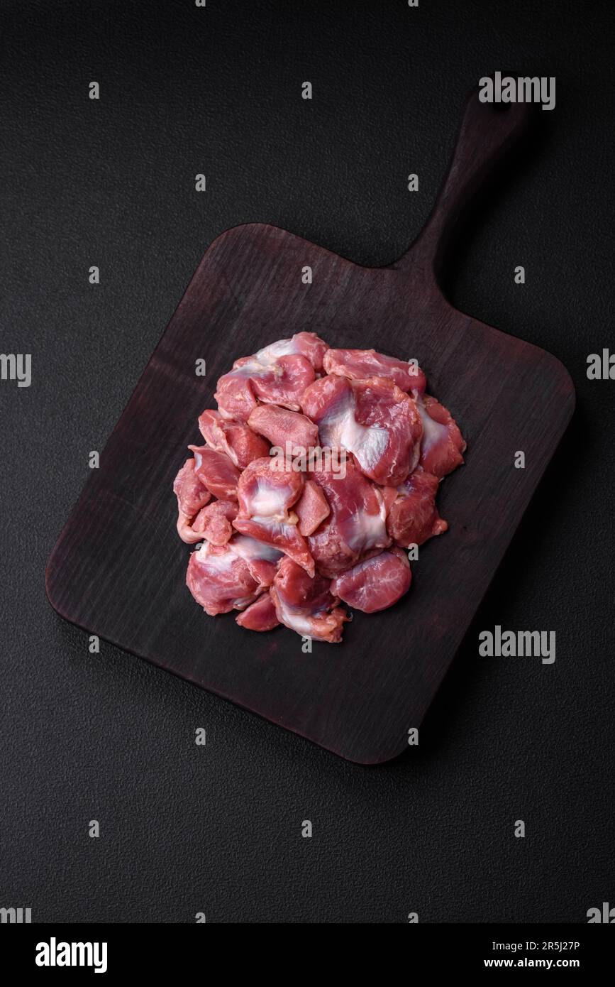 Raw chicken or turkey gizzards with salt, spices and herbs on a ...