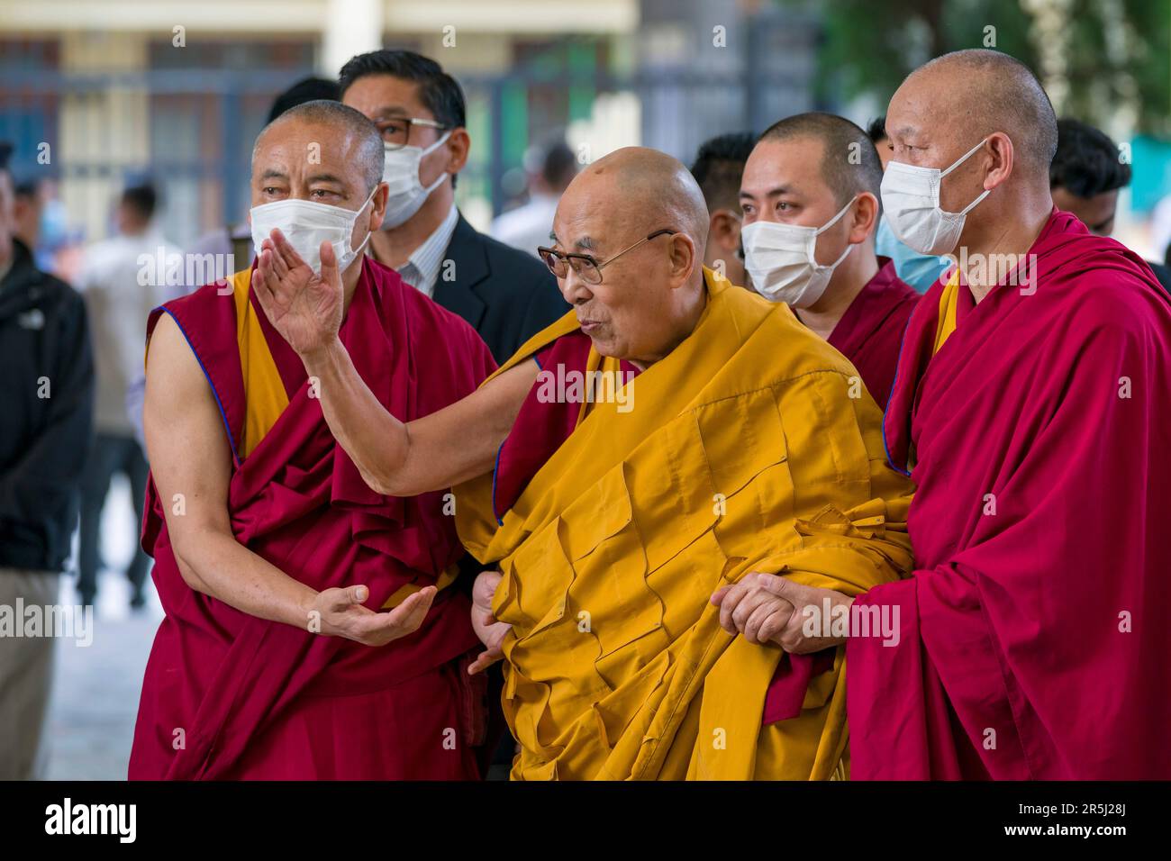 Tibetan spiritual leader the Dalai Lama, in yellow robe, greets ...