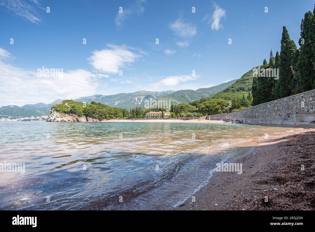 Waves lap on the pebbles and sand of Milocer Beach pictured between ...