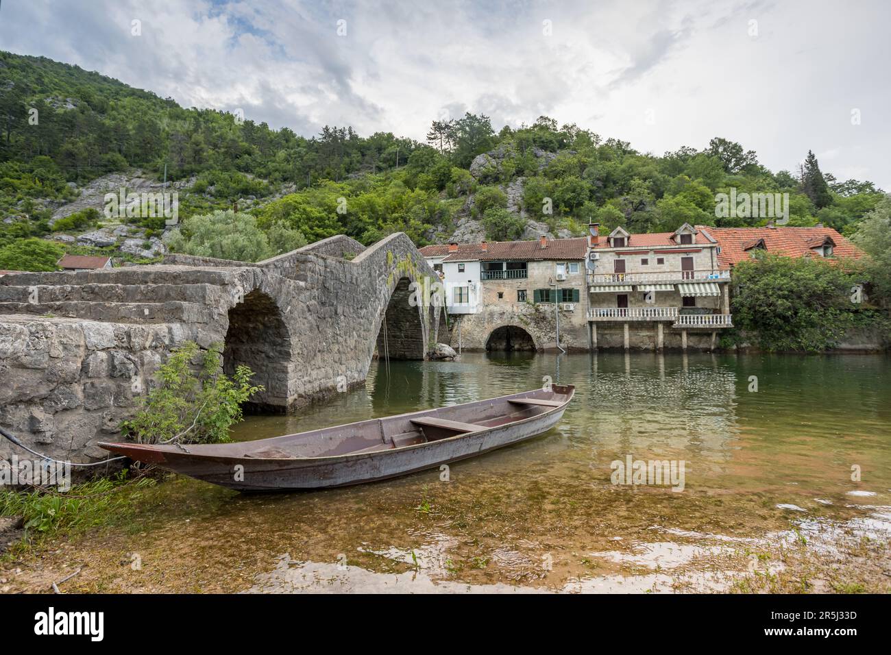 A small boat next to Rijeka Crnojevica bridge in Montenegro which is ...