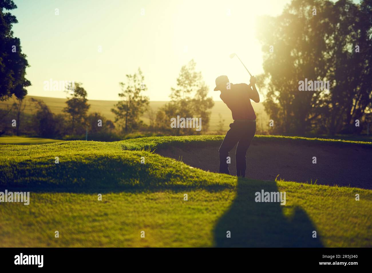Making the best of a bunker situation. a young man hitting the ball out ...