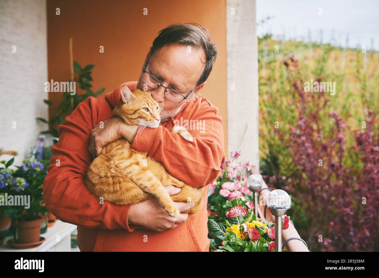 Portrait of middle age man holding cute ginger cat, resting on small ...