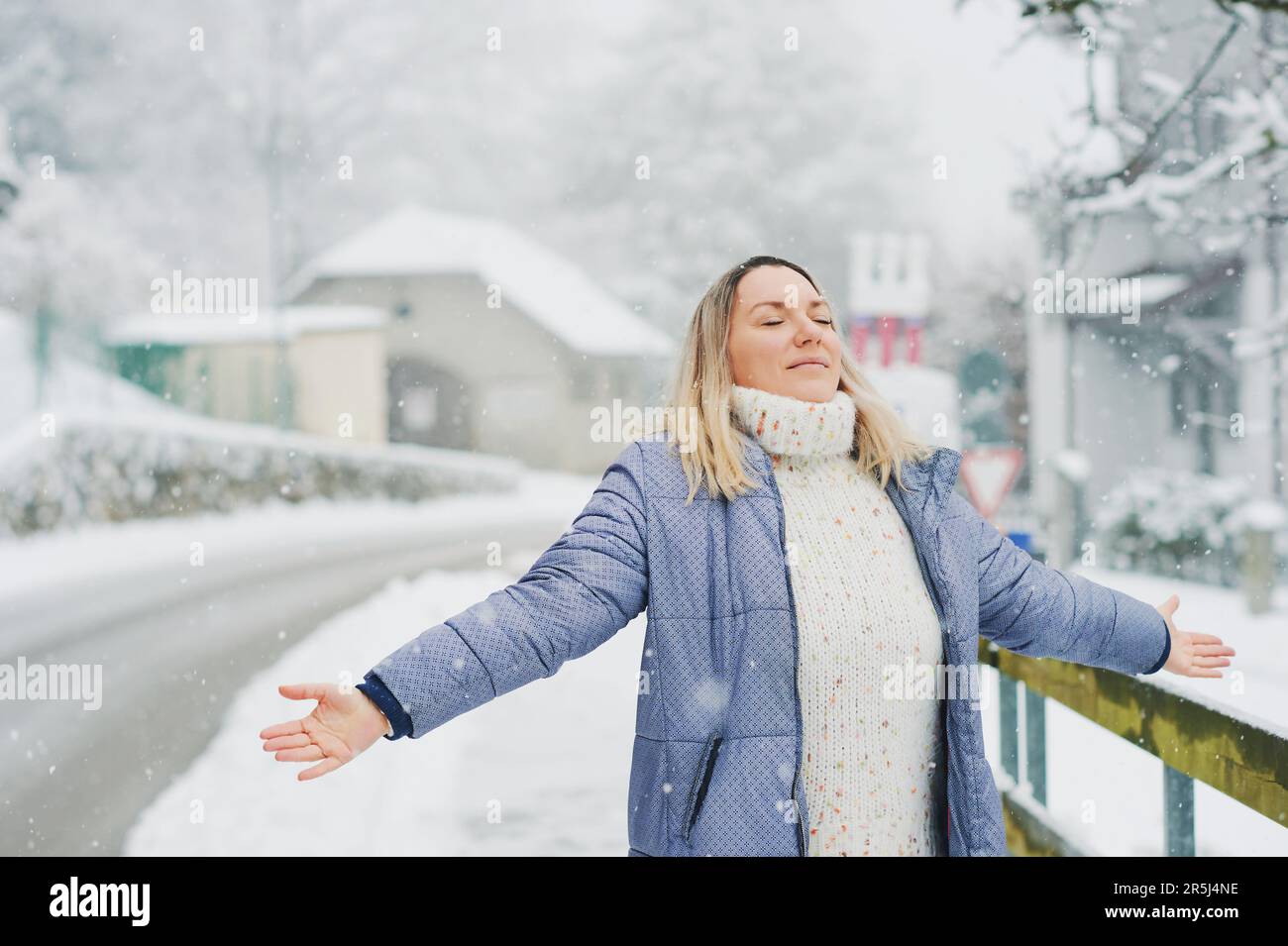 Happy mature woman enjoying nice winter day, arms wide open, wearing ...