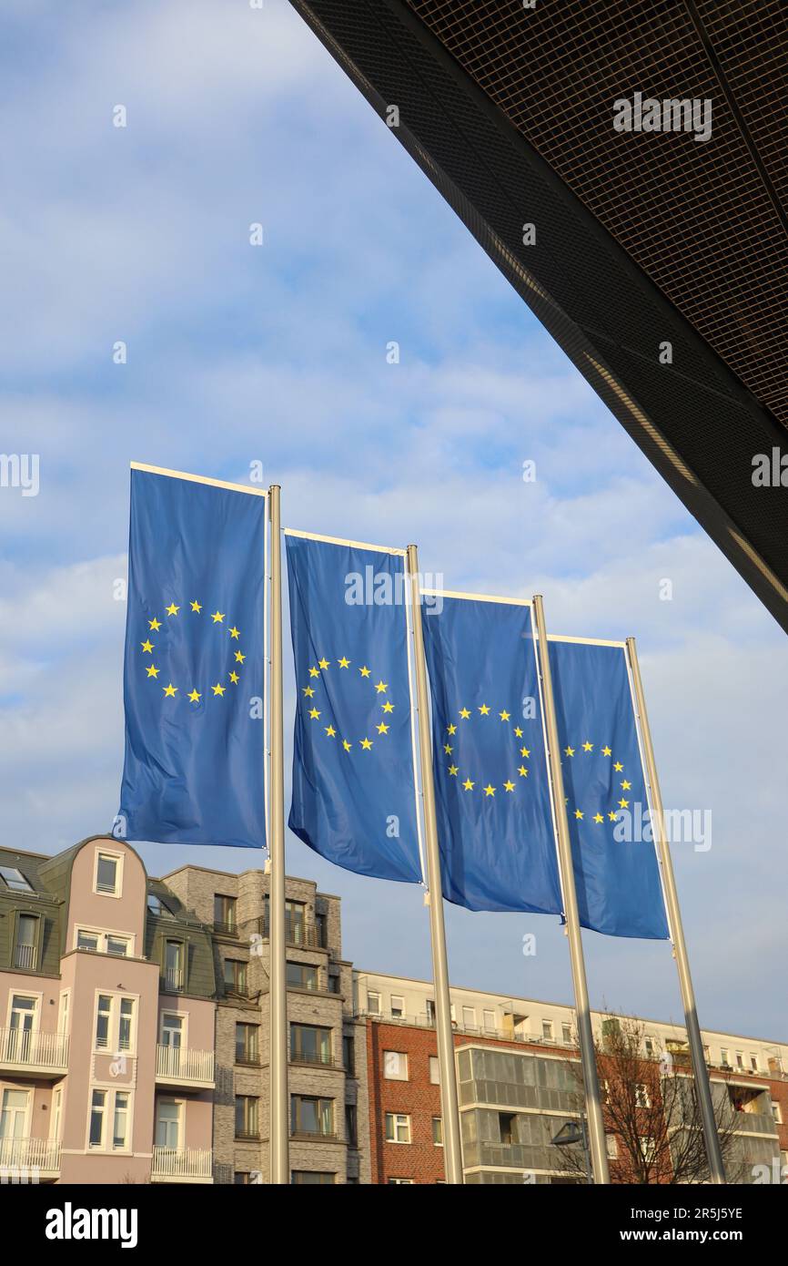 Four European Union Flags Waving with Buildings and Blue Sky as the ...