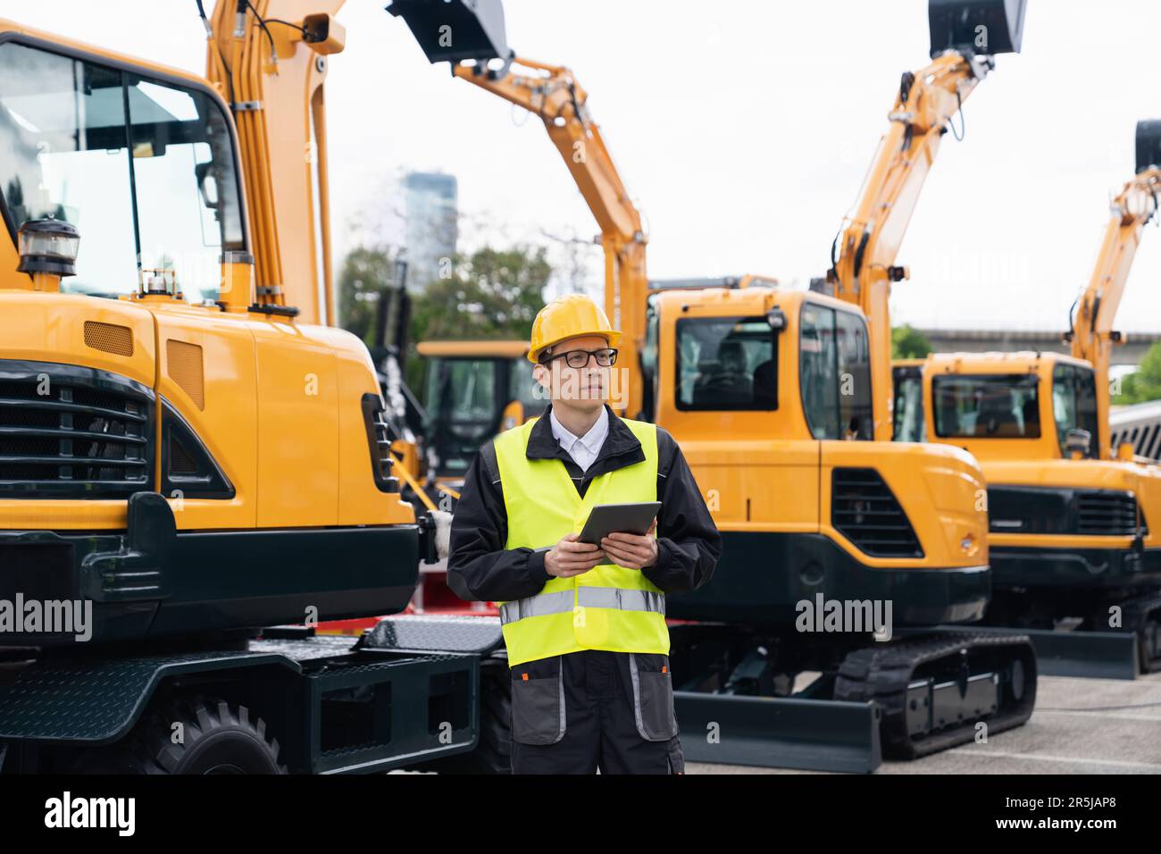 Engineer in a helmet with a digital tablet stands next to construction ...