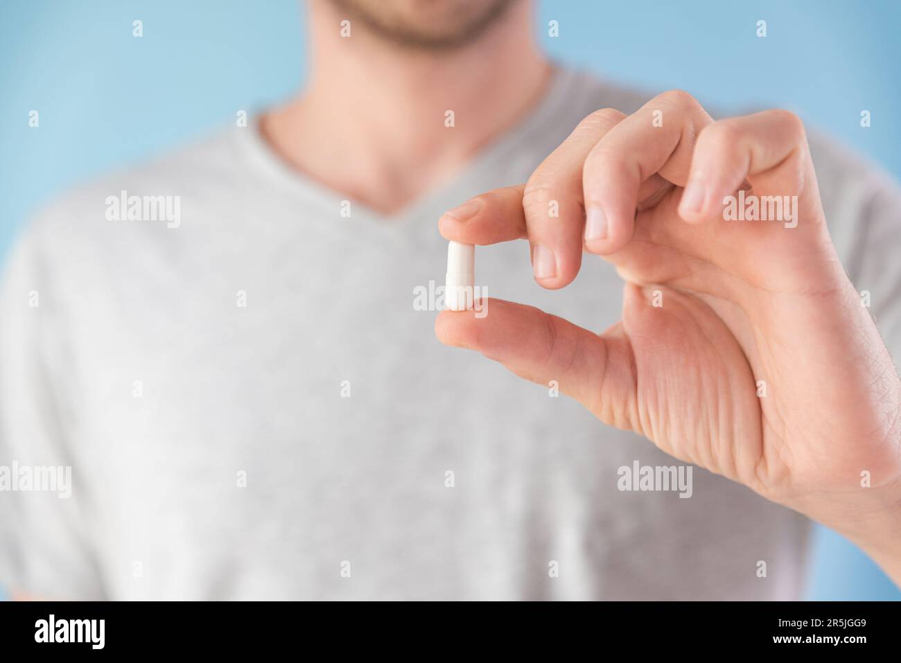 Man hold white capsule with collagen in male hand on blue background ...